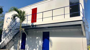 Um edifício moderno com fachada branca, uma faixa vertical vermelha e uma porta azul.