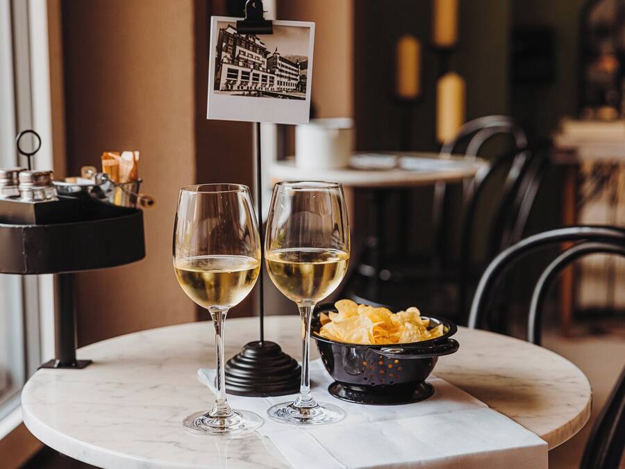 Uma mesa com duas taças de vinho e uma tigela de batata frita.