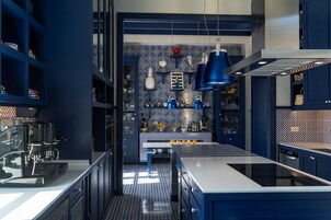 Cozinha moderna com armários azuis, uma ilha central e painel de fundo padronizado.