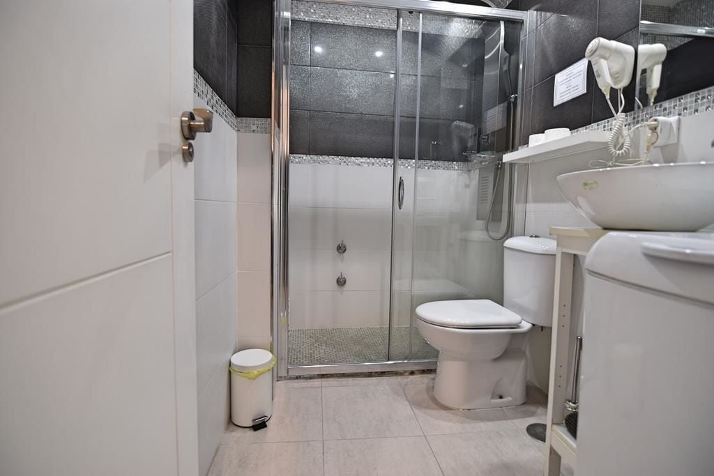 Uma casa de banho moderna com chuveiro com divisória de vidro, sanita e lavatório com espelho em cima.