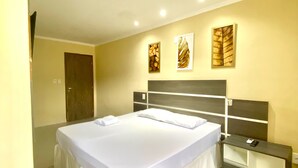 Quarto moderno com uma cama grande, uma mesinha de cabeceira e um painel de cabeceira.