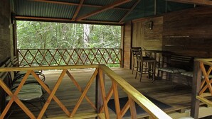 Um deck de madeira com guarda-corpo, uma mesa e duas cadeiras.