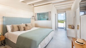 Quarto com cama, mesa de cabeceira, janela e vista para o exterior.