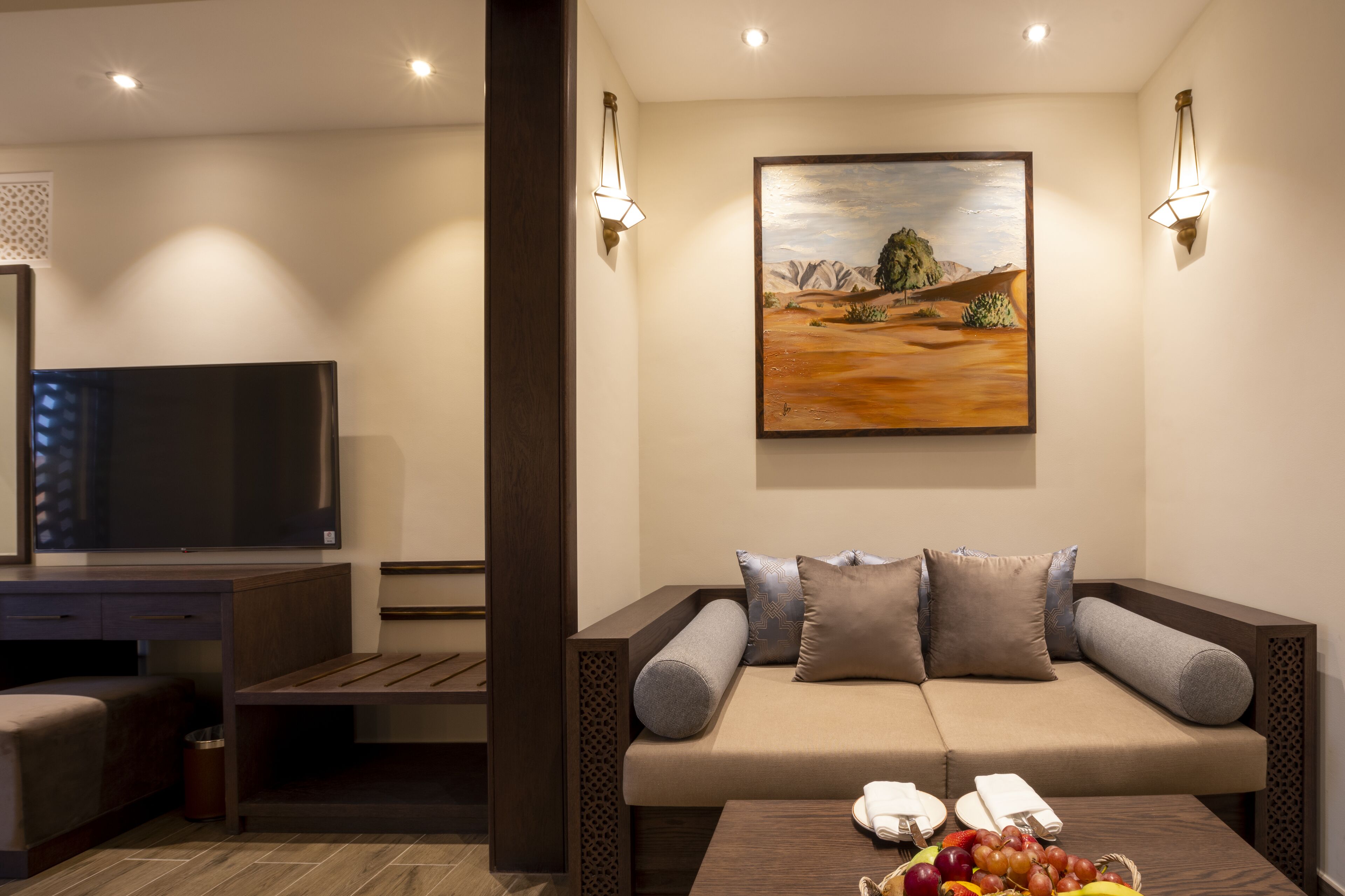Uma sala de estar moderna com um sofá, uma mesa de centro com frutas, um quadro e uma televisão.