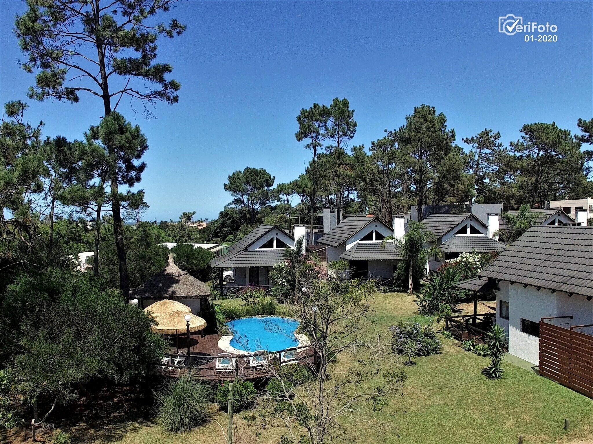 Uma área residencial com várias casas, uma piscina e árvores ao redor.