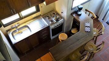 Cozinha compacta com fogão a gás, pia e mesa de jantar de madeira com cadeiras.