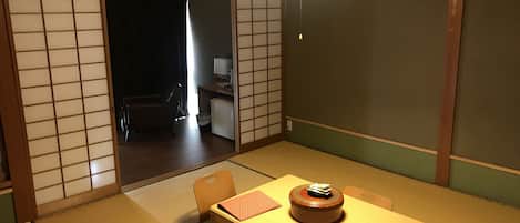 Um quarto tradicional japonês com tatames, uma mesa baixa com um objeto decorativo e portas deslizantes.