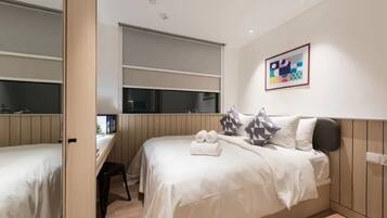 Quarto com cama, escrivaninha e prateleira na parede.