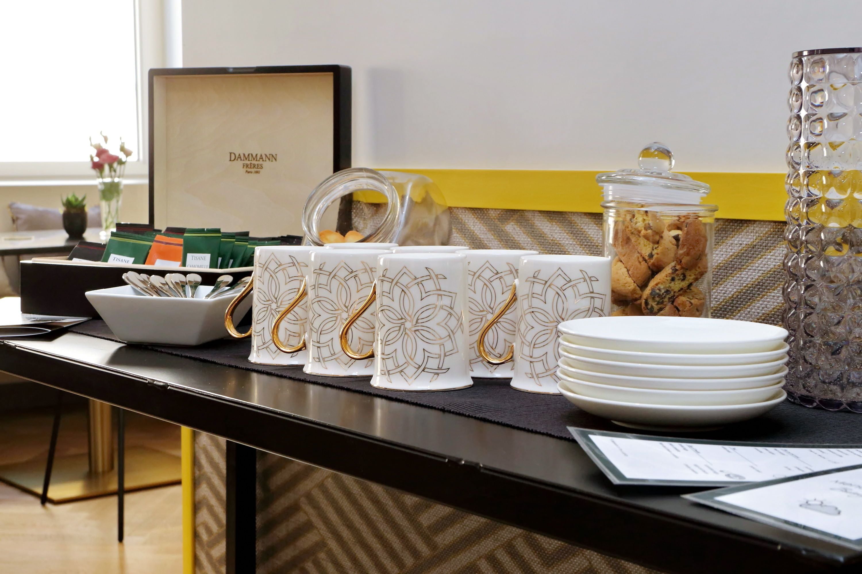Uma mesa de buffet bem organizada, com pratos, tigelas e um pote de biscoitos.