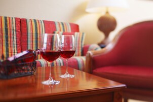 Uma mesa de madeira com duas taças de vinho tinto e um jarro para vinho.