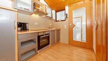 Uma cafeteira/bule, um frigorífico, um forno, uma placa de cozinha