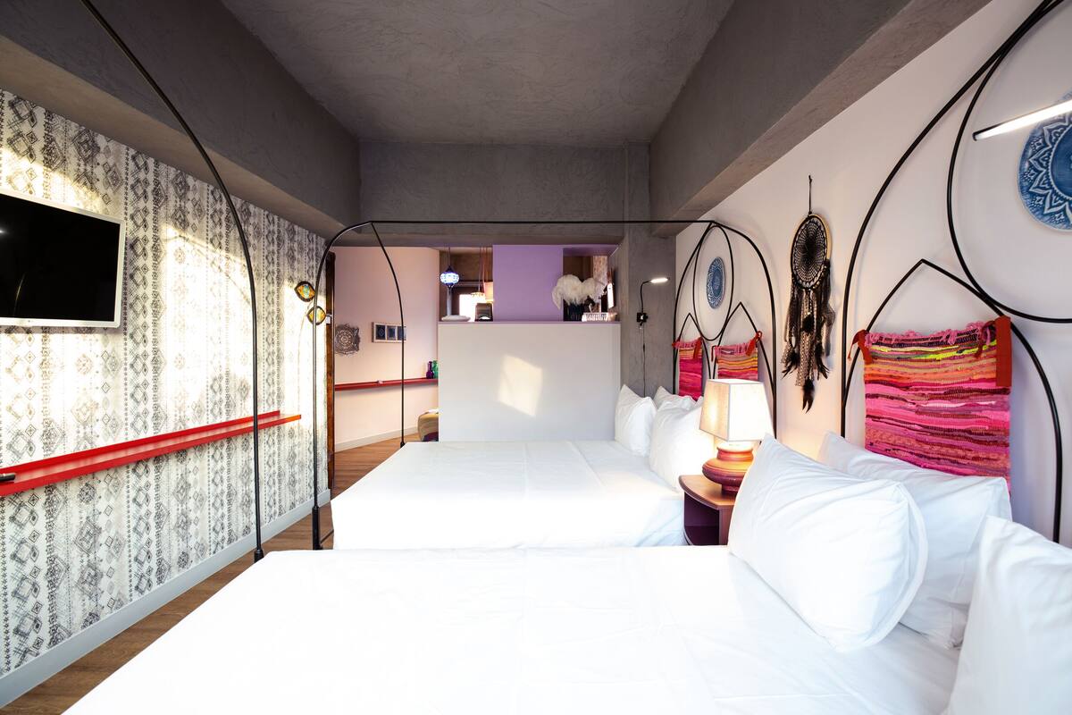 Quarto de hotel moderno com uma cama grande, uma televisão, uma escrivaninha e vista para a cidade.