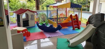 Uma área de recreação infantil com escorrega, estrutura de escalada e piscina de bolinhas.
