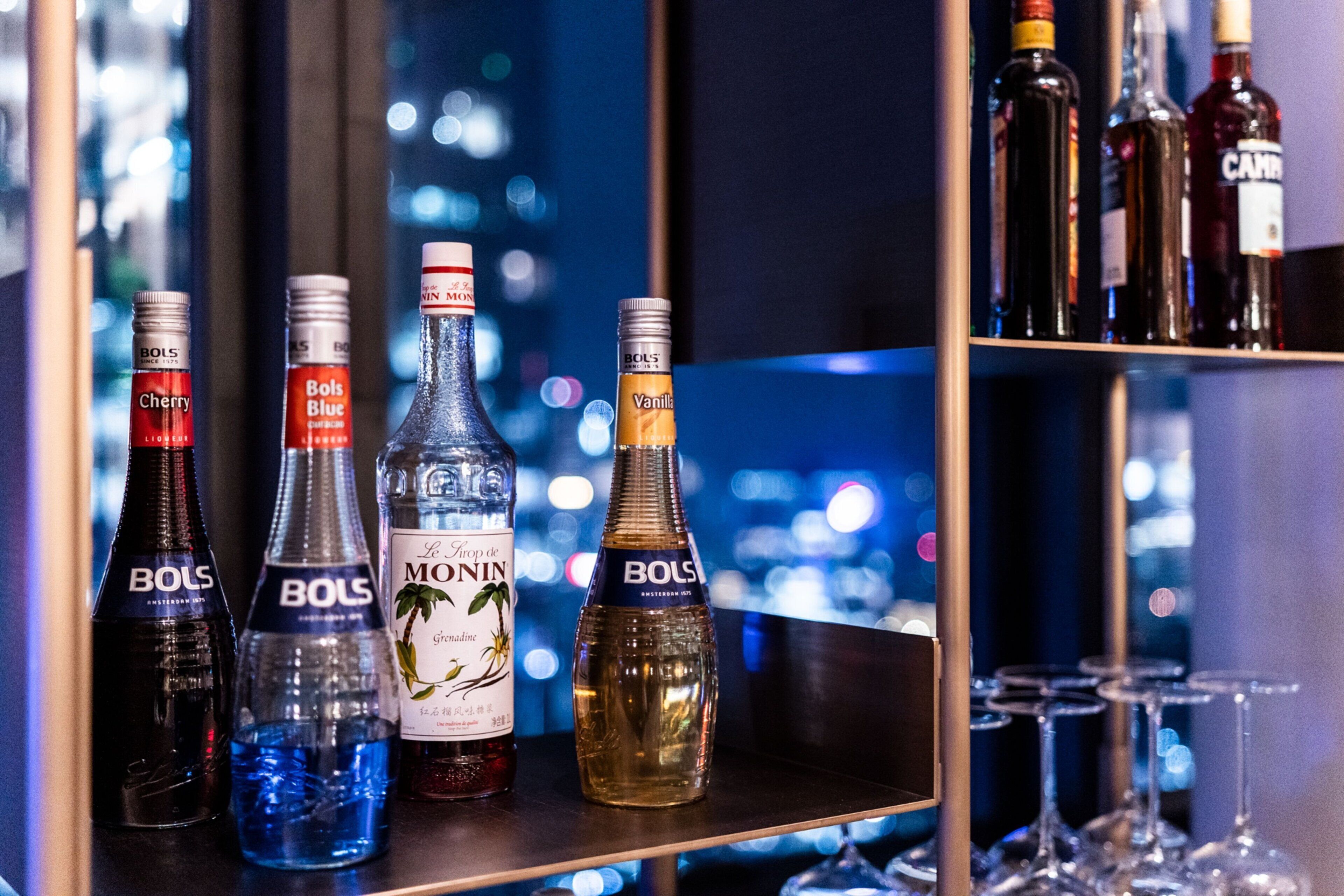 Uma área de bar com garrafas de bebidas alcoólicas e copos.