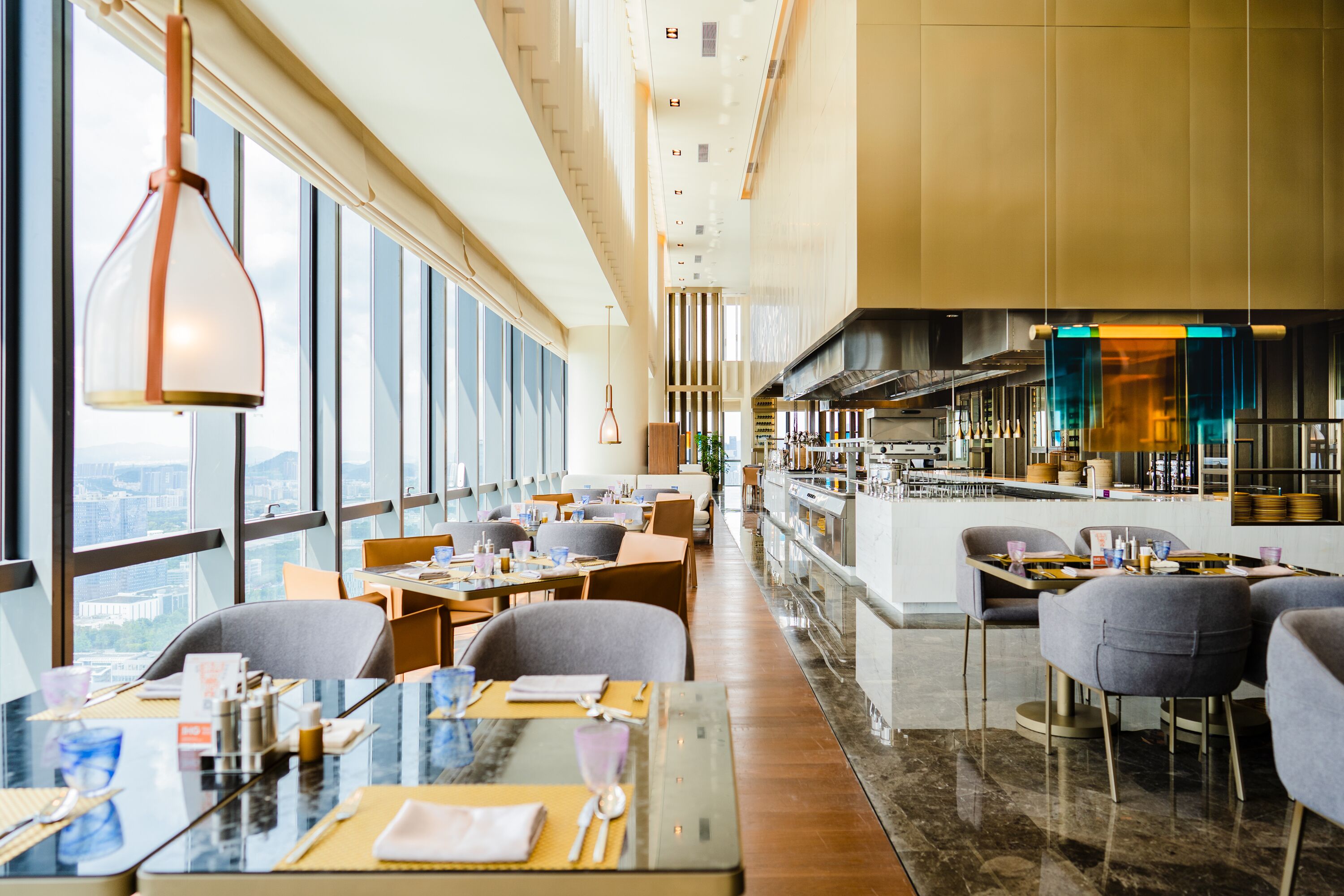 Um restaurante moderno com tetos altos, janelas amplas e um espaço de bar central.