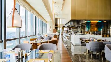Um restaurante moderno com tetos altos, janelas amplas e um espaço de bar central.