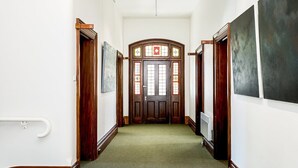 Um corredor com portas de madeira, parede branca e tapete verde.