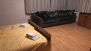 Quarto de hotel com cama, sofá e armário de madeira.