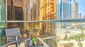 Varanda com guarda-corpo de vidro, vista para um horizonte urbano com edifícios modernos e céu limpo.