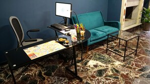 Quarto com escrivaninha, computador e sofá verde-água.