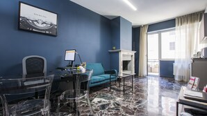 Quarto moderno com parede azul, uma escrivaninha com computador, sofá verde-água e lareira.