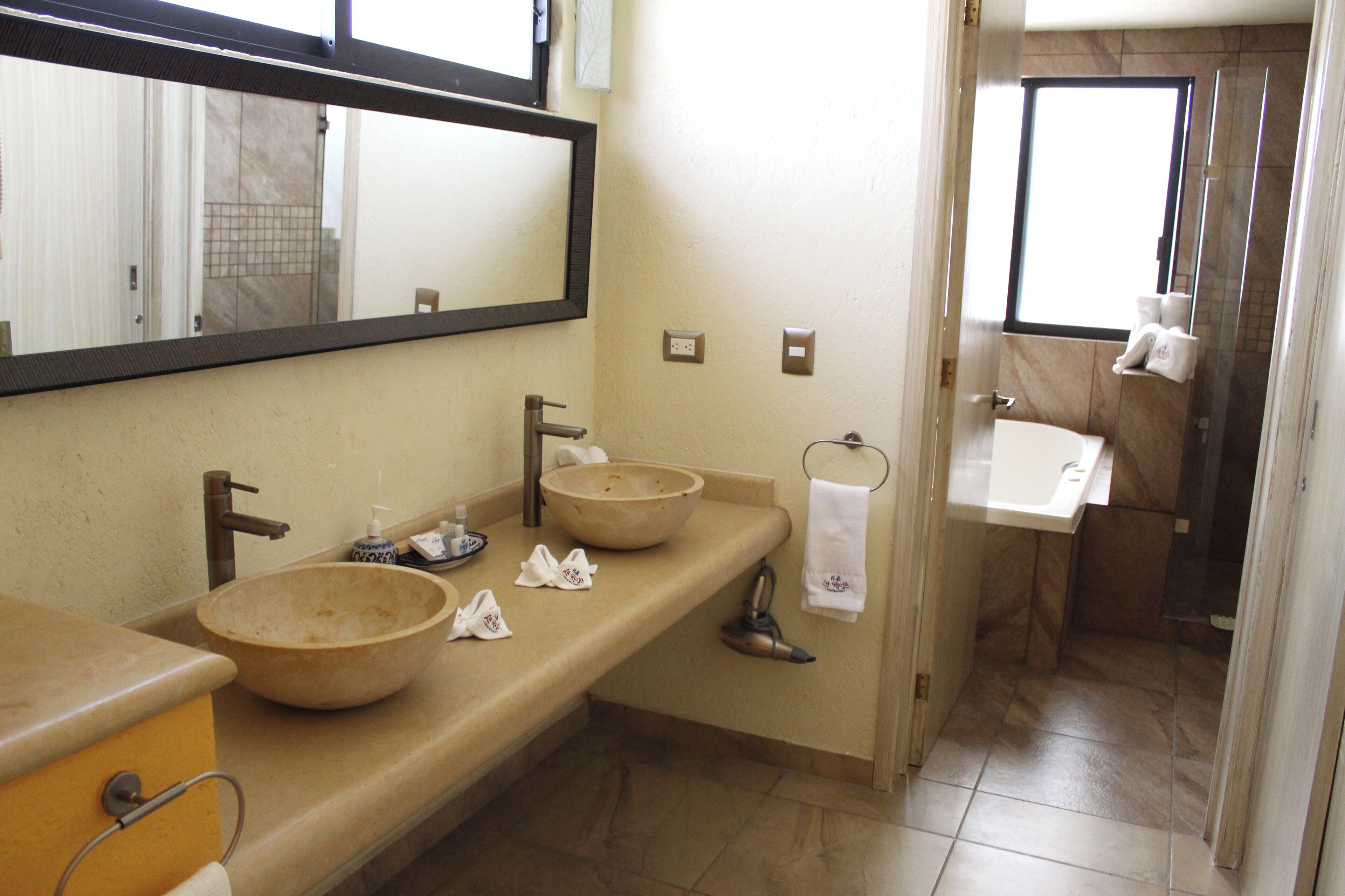 Casa de banho com duas pias, um espelho grande e zona de duche.