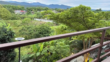 Uma varanda com vista para uma paisagem verde exuberante, um painel solar e uma cordilheira distante.