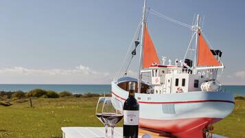 Um barco com casco branco e vermelho, uma garrafa de vinho e um copo sobre uma mesa.
