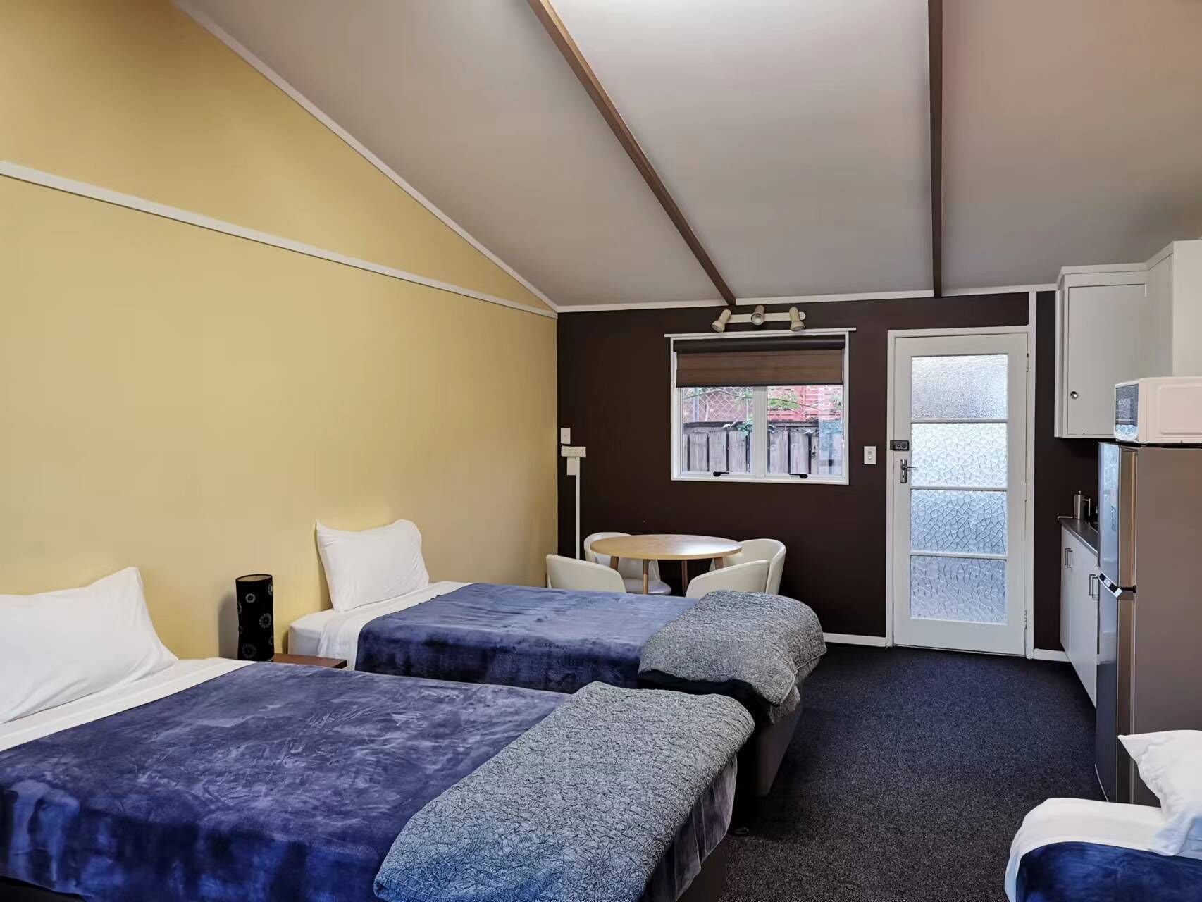 Quarto de hotel com duas camas, uma mesinha e janela com vista para o exterior.