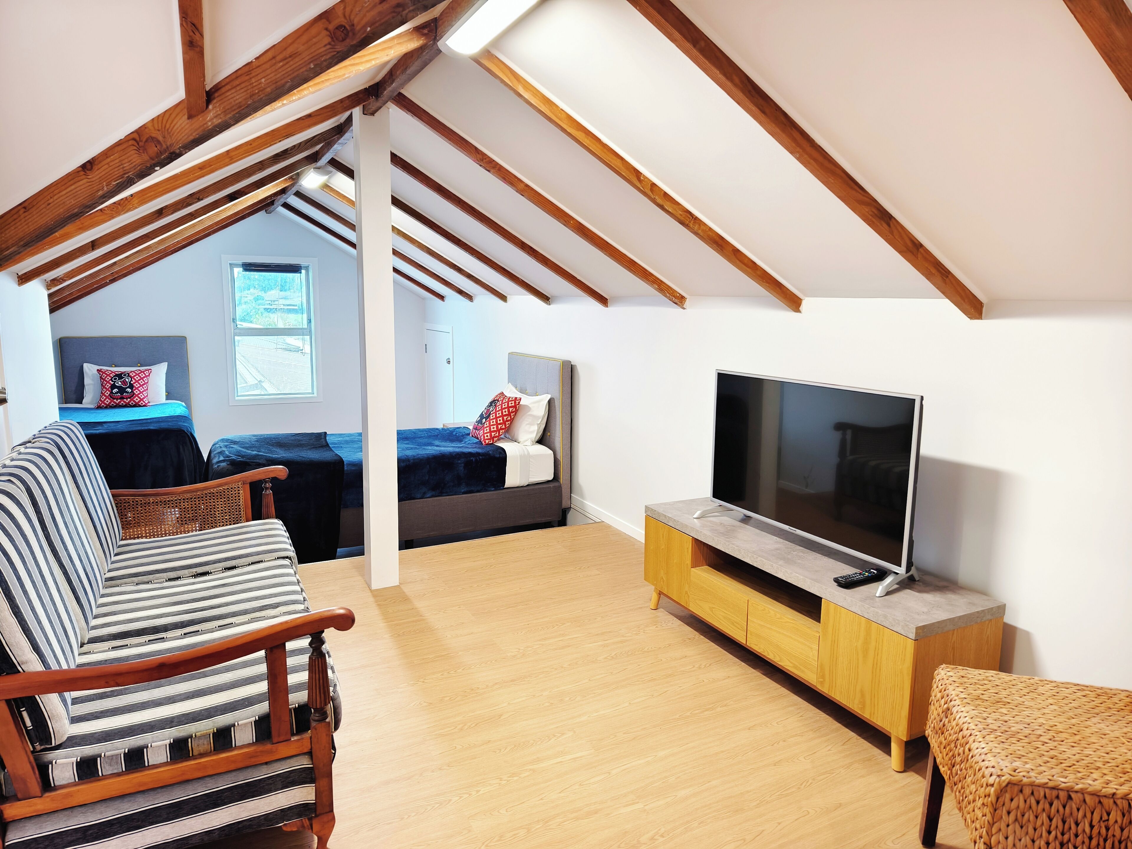 Quarto estilo loft com uma cama grande, uma televisão e uma cadeira de madeira.
