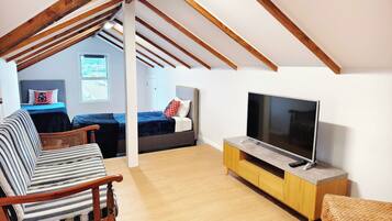 Quarto estilo loft com uma cama grande, uma televisão e uma cadeira de madeira.