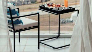 Varanda com mesa posta para o café da manhã, com vista para a praia e o oceano.