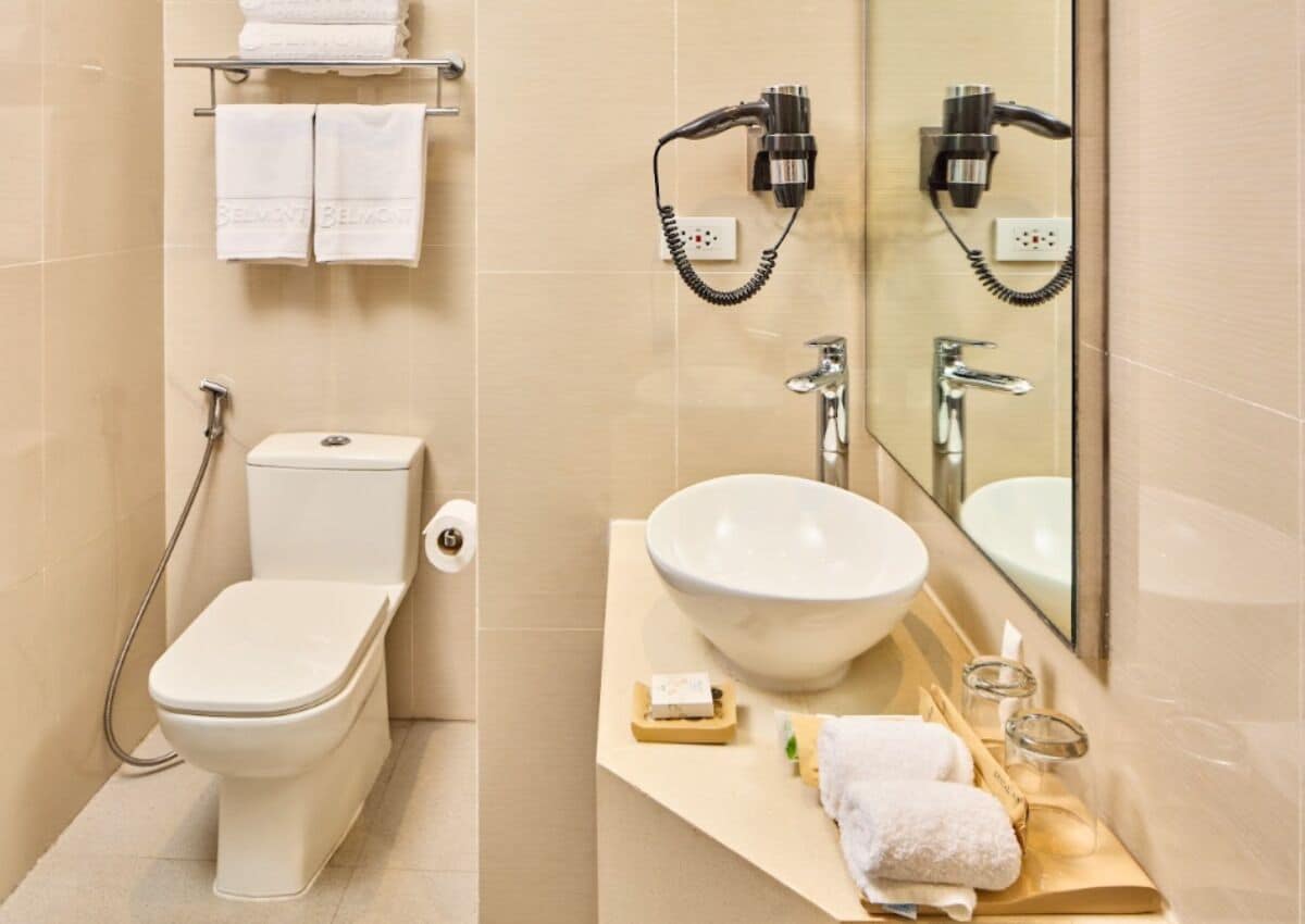 Uma casa de banho moderna com sanita, bidé e um espelho grande.