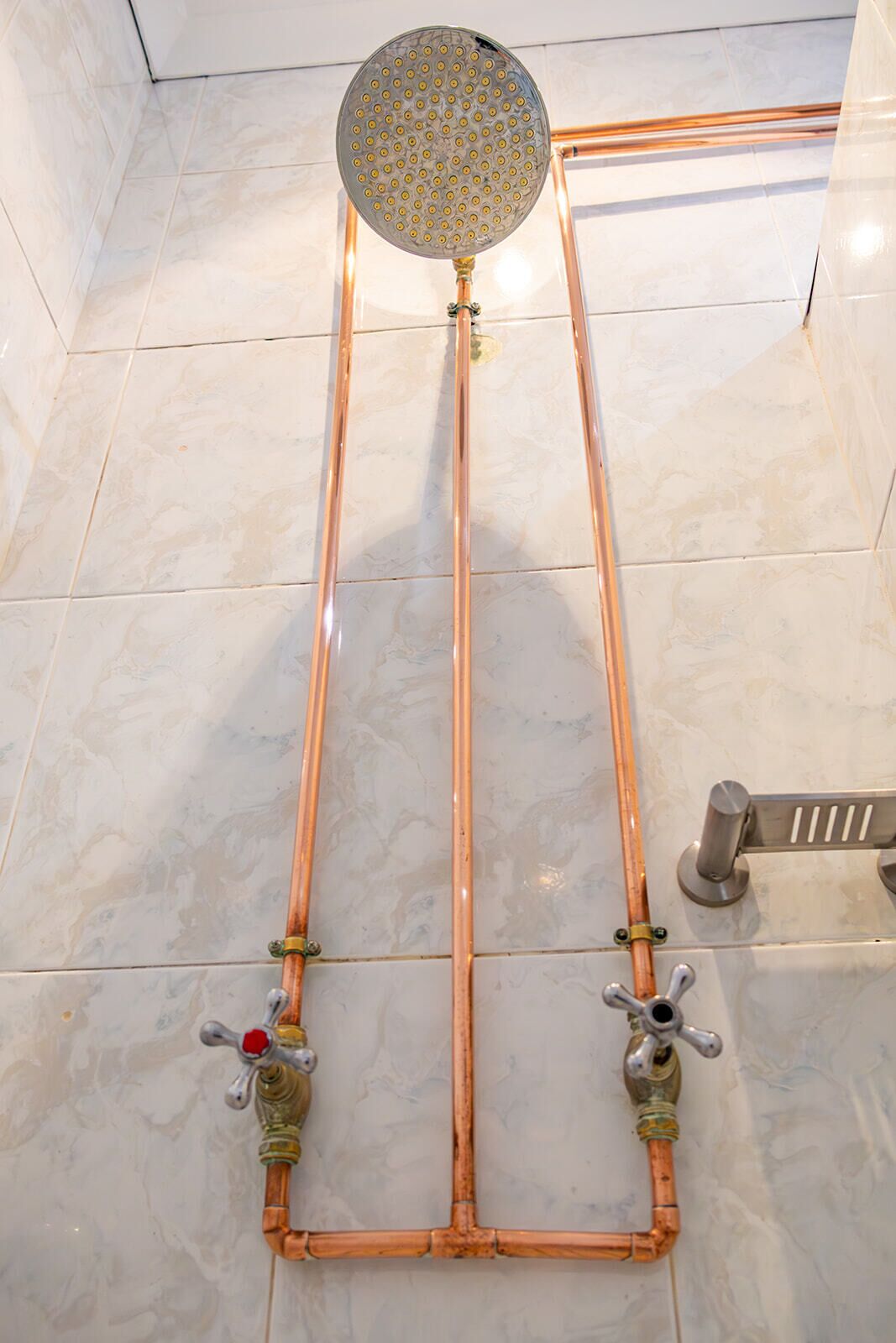 Casa de banho com sistema de chuveiro em cobre, incluindo um chuveiro e duas torneiras.