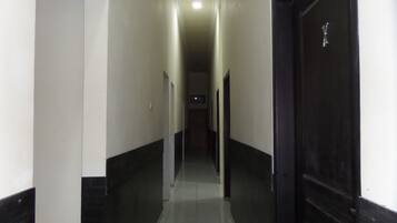 Um corredor com portas em ambos os lados, piso de azulejos e um luminário no teto.