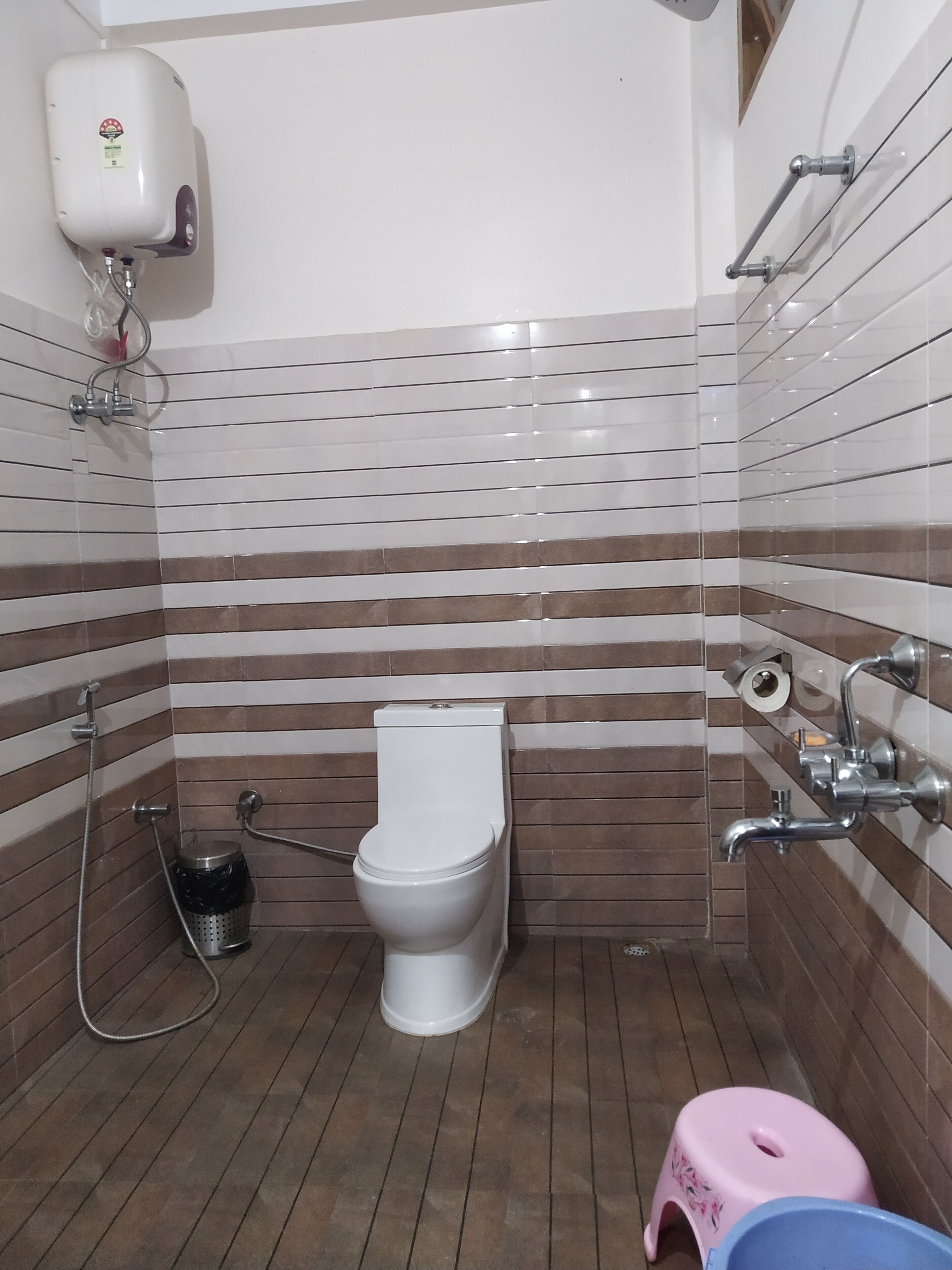 Uma casa de banho pequena com sanita, chuveiro e secador de mãos.
