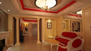 Um quarto espaçoso com um sofá vermelho, uma mesa de centro de madeira e uma lareira.
