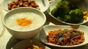 Uma mesa posta com diversos pratos, incluindo uma tigela de mingau, um prato de legumes e uma chaleira.
