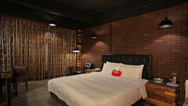 Quarto de hotel moderno com uma cama grande, uma mesa e uma cadeira.