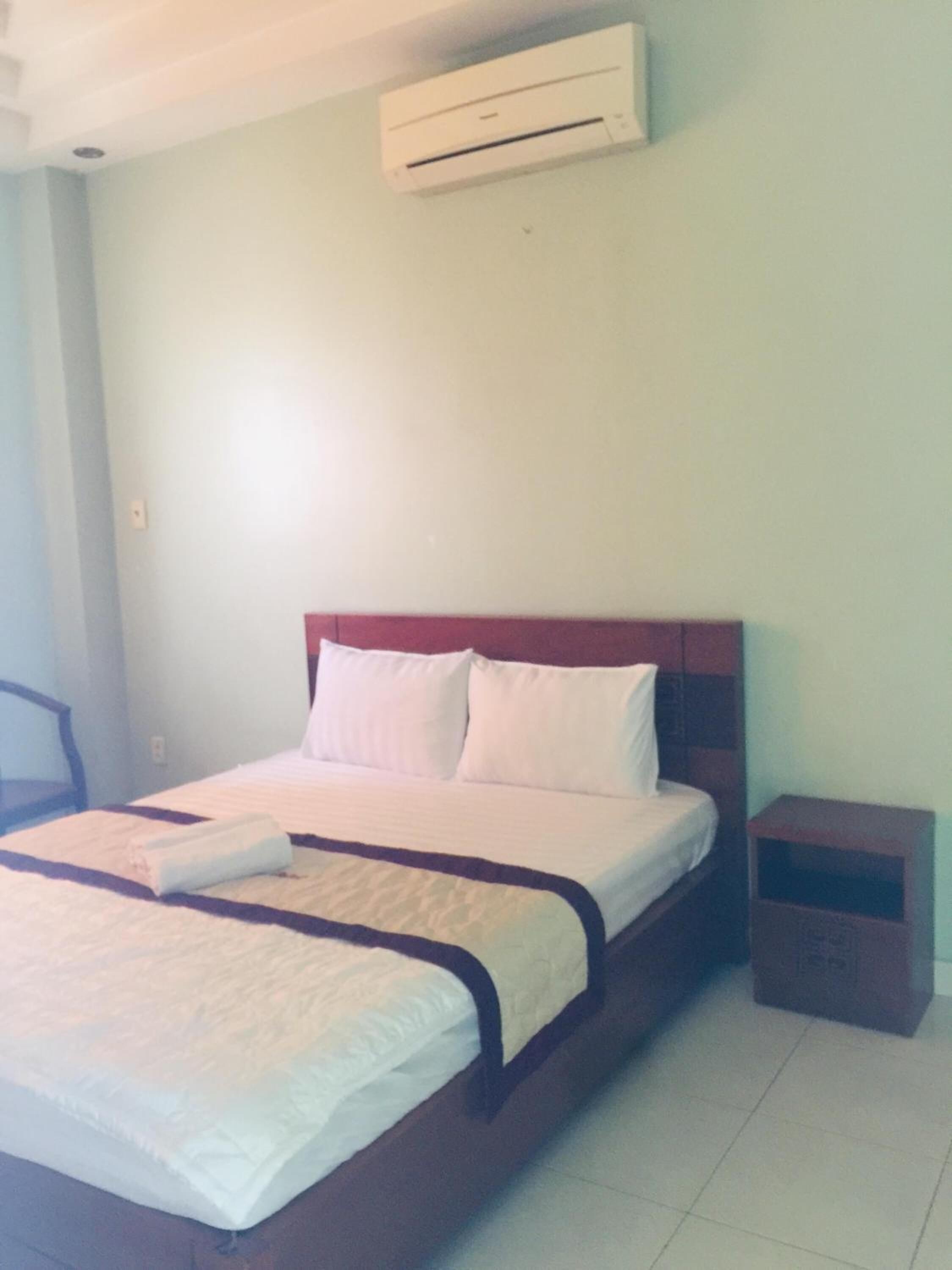 Quarto de hotel com cama, mesa de cabeceira e aparelho de ar condicionado na parede.