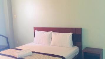 Quarto de hotel com cama, mesa de cabeceira e aparelho de ar condicionado na parede.