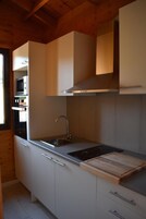 Uma cozinha compacta com armários brancos, pia de aço inoxidável, micro-ondas e forno.