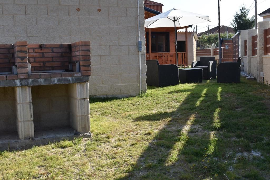 Um quintal com churrasqueira, móveis de exterior e um espaço coberto de varanda.