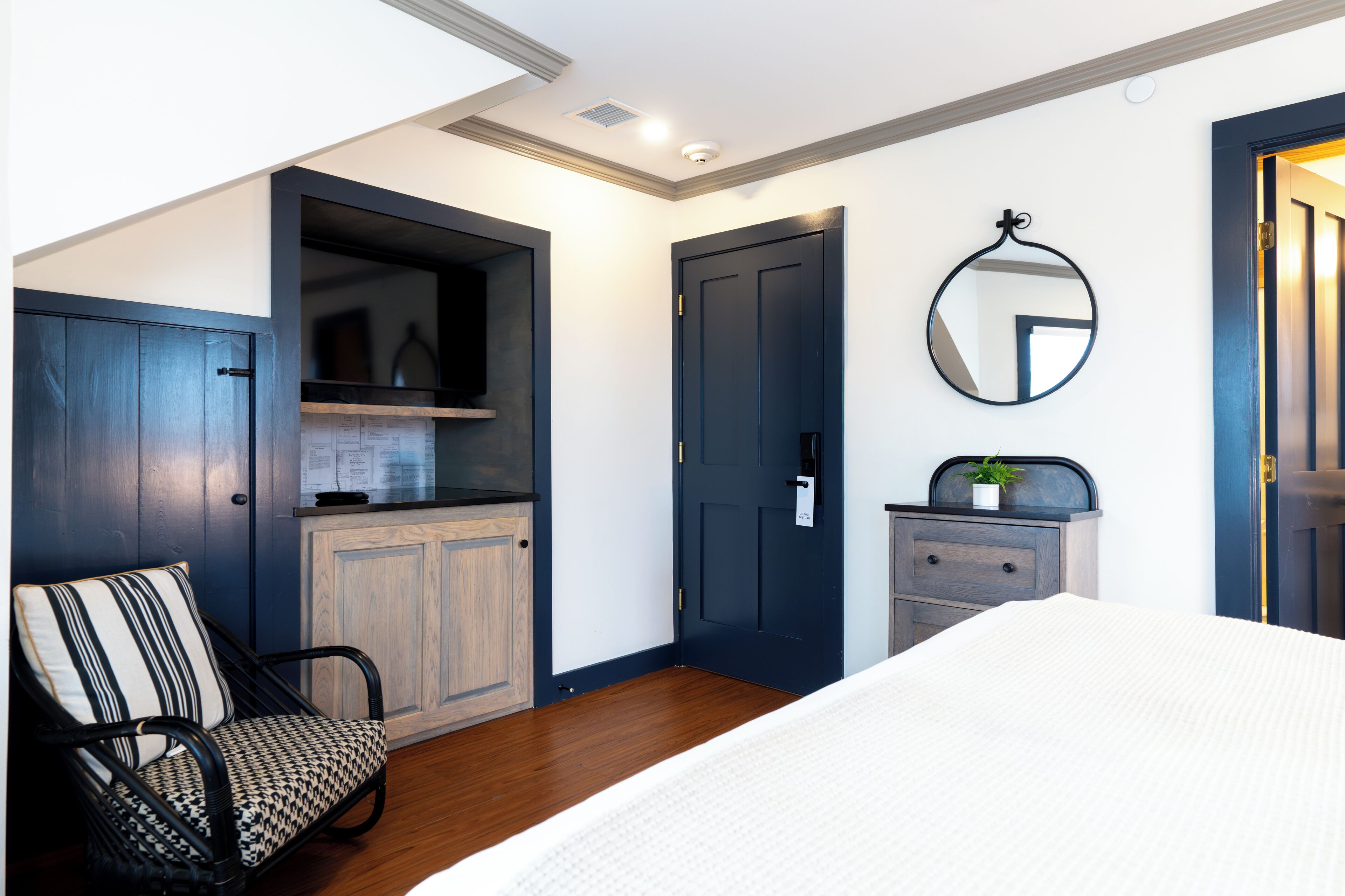 Quarto com cama, cadeira, penteadeira, espelho e porta.