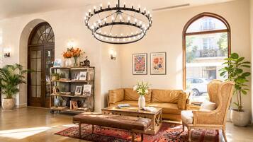 Uma sala de estar espaçosa com sofá de couro, mesa de centro, estante de livros, lustre e janelas amplas.