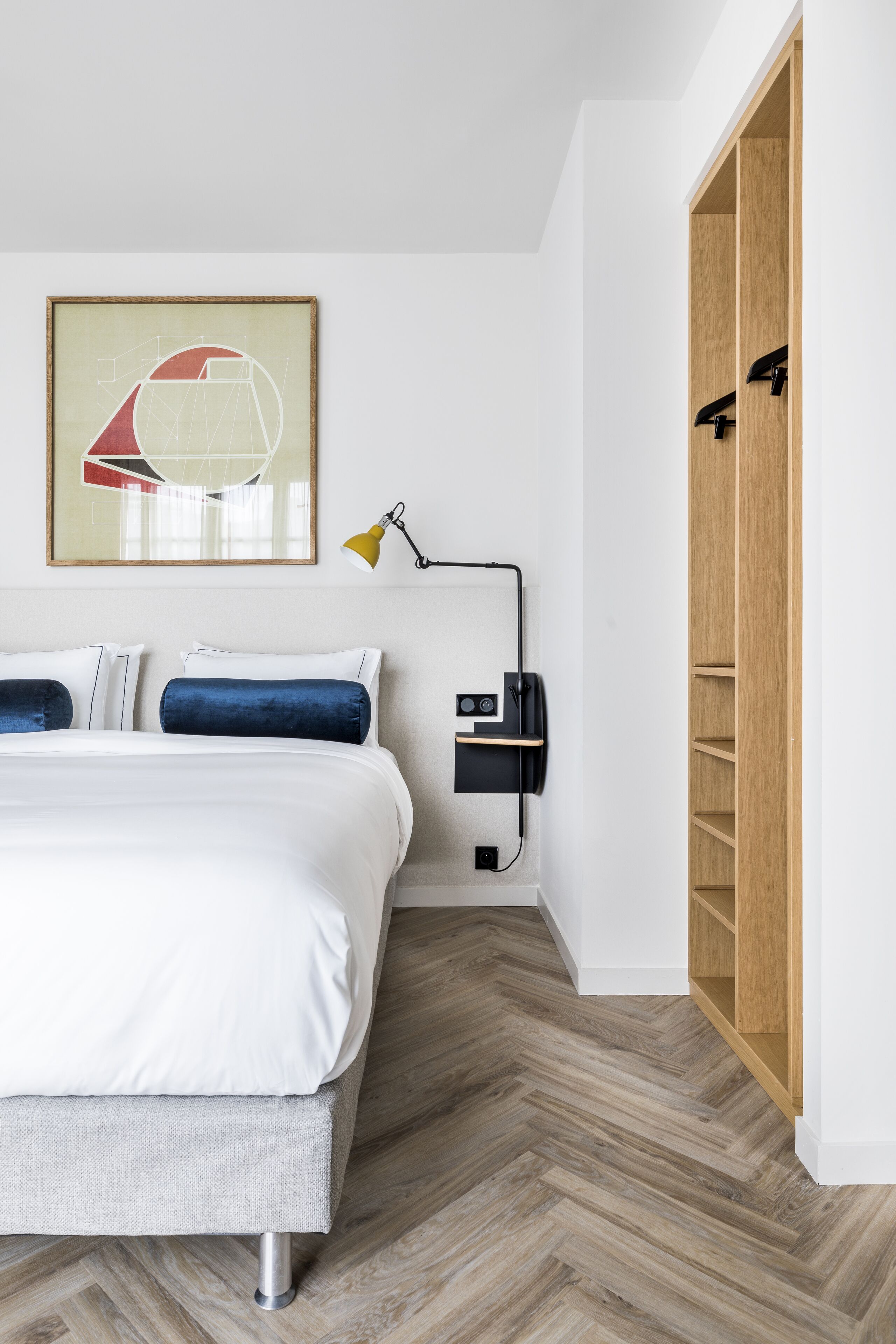 Quarto moderno com cama, mesa de cabeceira, luminária e guarda-roupa de madeira.