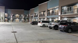 Garagem de estacionamento com vários andares e diversos carros estacionados, iluminada por luzes no teto.