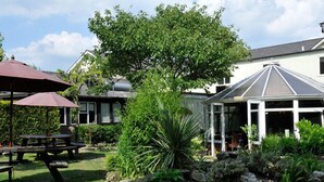 Um jardim com mesas de piquenique e um gazebo.