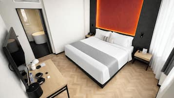 Quarto de hotel moderno com cama, mesas de cabeceira, escrivaninha e espelho.