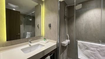 Uma casa de banho moderna com um espelho grande, uma pia, um chuveiro e um porta-toalhas.